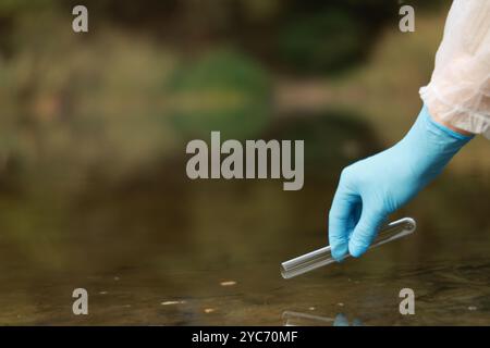 Examination of water quality. Researcher taking water sample from lake ...