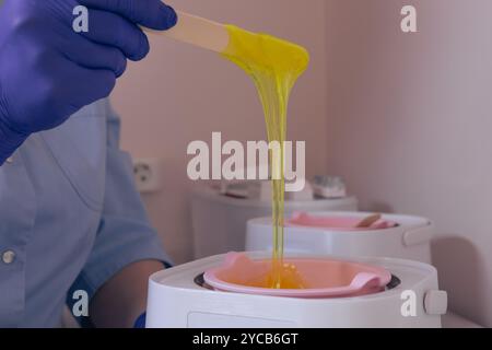 Waxing procedure with pink wax in a beauty salon during afternoon hours ...