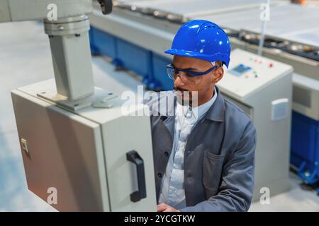 African American engineer with a blue helmet and safety goggles ...