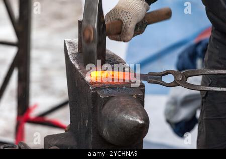 Blacksmith forges a red-hot iron in the forge. Forging hammer of metal ...