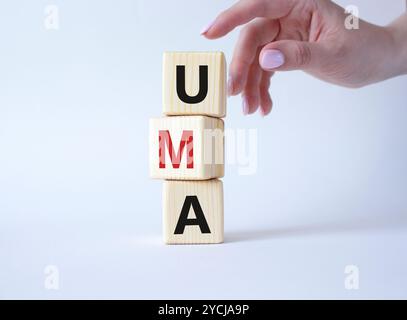 UMA - Unified Managed Account. Wooden cubes with word UMA. Businessman ...