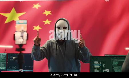 Anonymous hacker expert in a Chinese hacking high tech office, digital ...