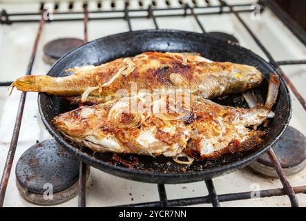 Old frying pan with fried fish on wooden table Stock Photo - Alamy