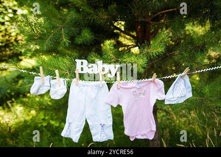 Infant girl clothing on rope. Toddler girl top and pants hanging on ...