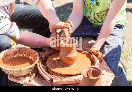 Teacher helps his student to work with red clay. Work on the potter's ...