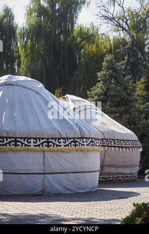 Two yurts surrounded by lush trees foliage in Bishkek city park ...