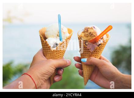 Female hands with different sweet ice-cream in waffle cones on red ...