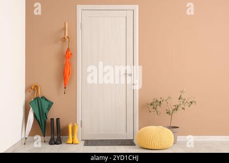 Interior of hallway with rubber boots and umbrellas near light wall ...