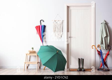 Interior of hallway with rubber boots and umbrellas near light wall ...