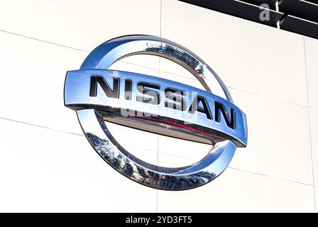 Official dealership sign of Nissan on the wall of the office building ...