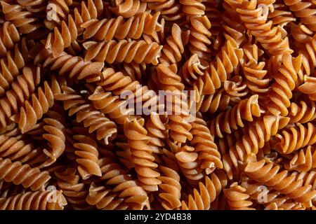 Lot of whole twisted raw pasta gemelli in wooden bowl isolated on white ...