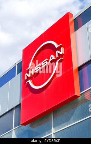 Official dealership sign of Nissan on the wall of the office building ...