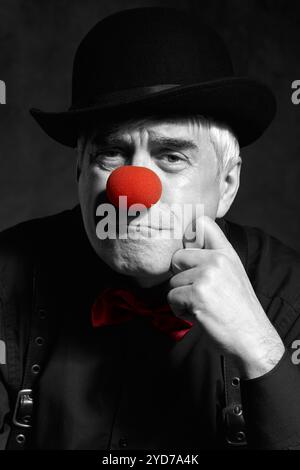Dramatic selective color portrait of a sad clown against a dark ...