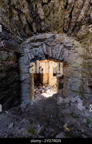 A dimly lit stone passageway leading to an ancient structure in Merida ...