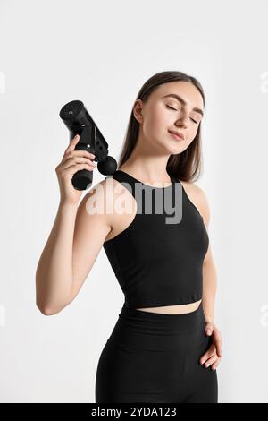 Young woman using percussive massage device at home Stock Photo - Alamy