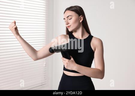 Young woman using percussive massage device at home Stock Photo - Alamy