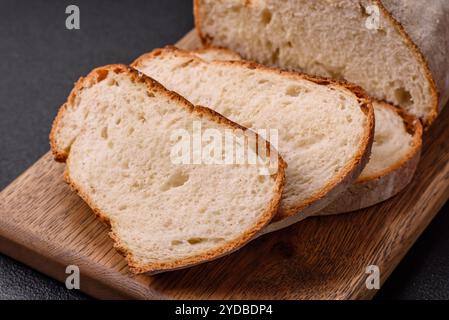 A loaf of brown bread with grains of cereals on a wooden cutting board ...