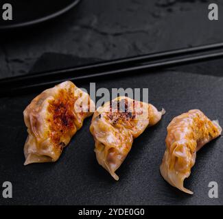 Black board of fried Japanese gyoza with bowls of sauces and seaweed ...