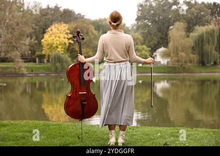 Woman with cello in park, back view. Classic musical instrument Stock ...
