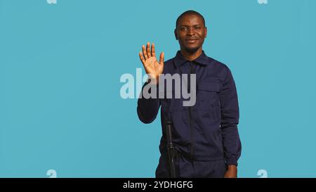 Upbeat security guard greeting people, preventing criminal activity and ...