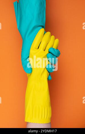 Professional cleaner wearing orange protective gloves sanitizing white ...
