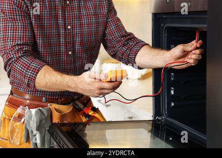 Repairman testing oven element with multimeter in kitchen Stock Photo ...