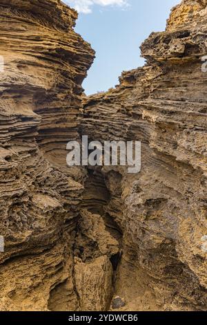 Rocky coastal cliff with layered sediment and ocean waves in northern ...