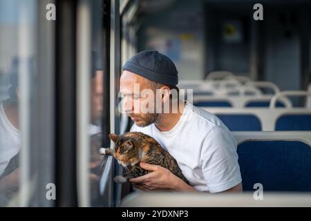 Attentive caring man pet owner traveling with fluffy cat in hands ...
