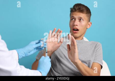 Needle phobia. Scared man making stop gesture near doctor with syringe ...