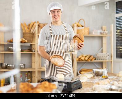 Happy male baker posing with basket of freshly baked baguettes in ...