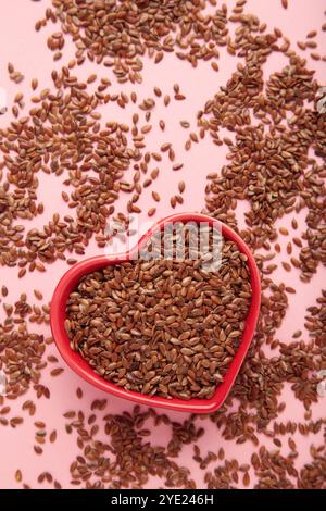 Heart shaped brown linseed, flax seeds on wooden background, concept for healthy nutrition ...
