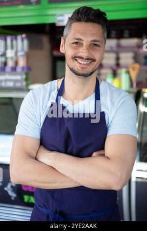 Smiling ice cream store employee standing behind the counter in the ...