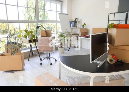 Desks with plants and boxes in office on moving day Stock Photo - Alamy