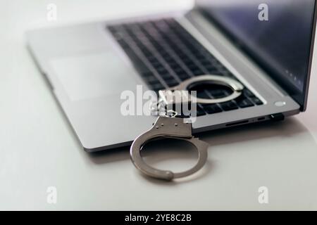 Handcuffs and laptop. Online piracy, fraud phishing, internet safety ...