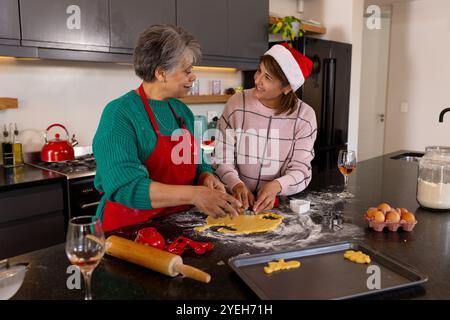 Senior female friends baking christmas cookies together, laughing, at ...