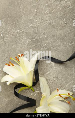 White liles flowers with black ribbon. Mourning or funeral background ...