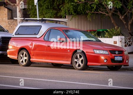 A red Holden ute parked on a suburban street, featuring a silver canopy ...