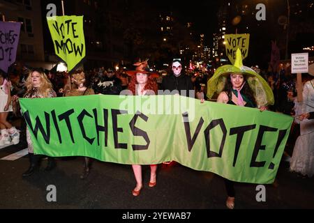 A group of women dressed as witches carrying a banner and signs march ...