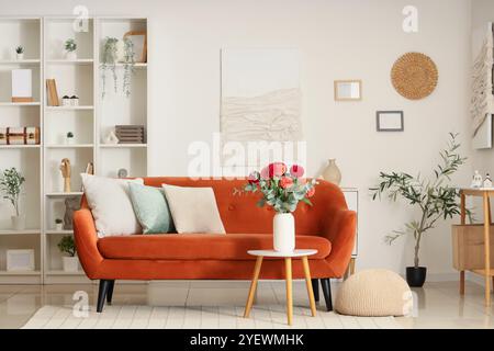 Comfortable sofa and coffee table with dahlia flowers in vase in living ...