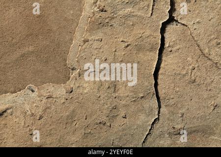 Crack in the concrete cladding of an old house. Rough, uneven surface ...