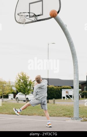 Teenage boy hits goal playing basketball on village sports ground Stock ...