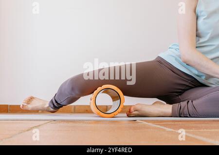 Woman doing self myofascial release of inner thigh with foam roller ...