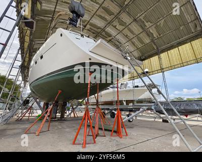 A boat is carefully lifted under a covered structure Stock Photo - Alamy