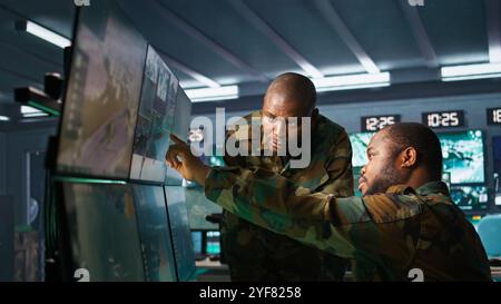 Team of soldiers looking at screens in command center housing ...