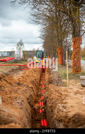 Network cables in red corrugated pipe are buried underground on the ...