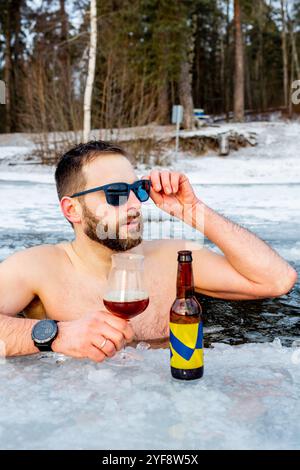 Winter swimming. A cheerful man with a beer takes cold baths. Vacation ...