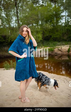 Woman in Blue Poncho poses by Riverside with Her Dog Stock Photo - Alamy