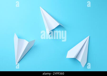 Light blue paper planes with flight paths on white background. Dashed ...