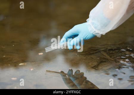 Examination of water quality. Researcher taking water sample from lake ...