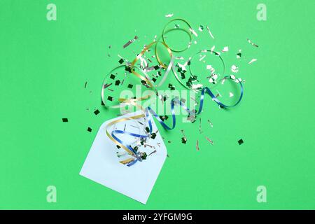 Shiny confetti and party streamers flying out of envelope on light blue ...